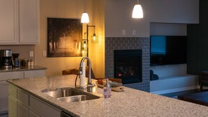 Cozinha moderna com bancadas de granito, eletrodomésticos de aço inoxidável e iluminação pendente.