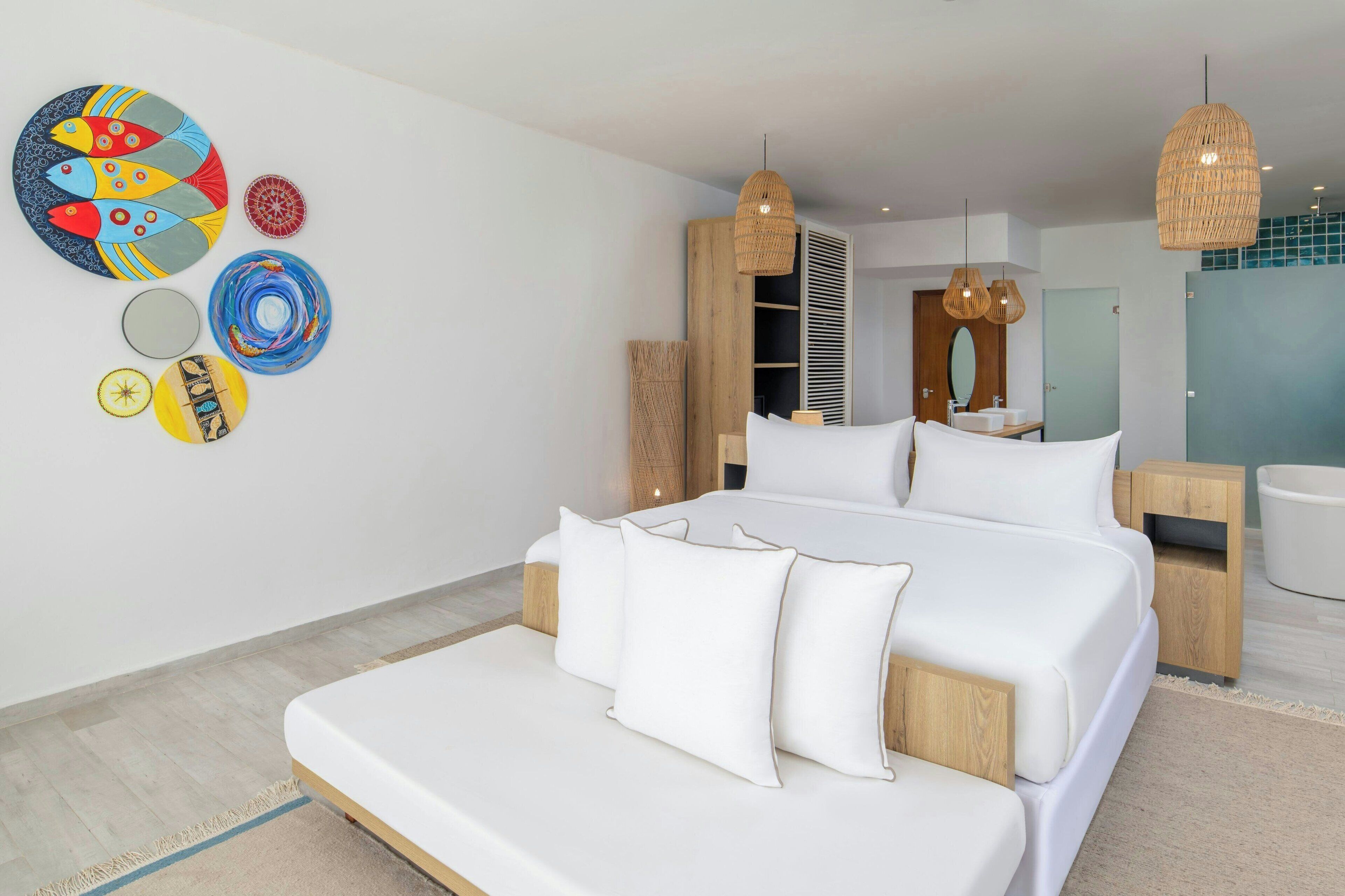 Quarto de hotel moderno com uma cama grande, um armário de madeira, um banheiro com espelho e uma obra de arte decorativa na parede.