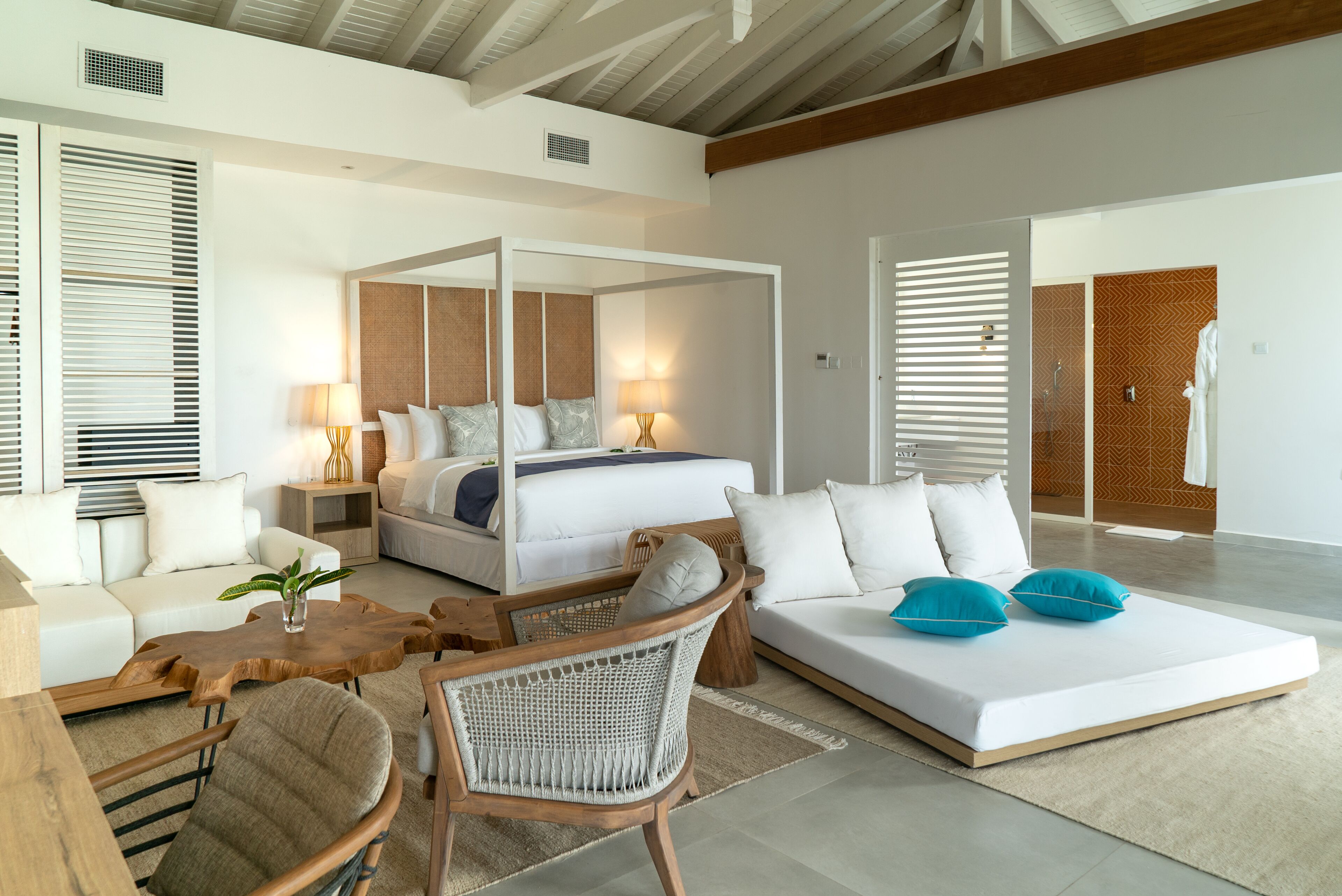 Quarto moderno com cama de dossel, um sofá, mesa de centro de madeira e um espaço de estar com cadeiras.