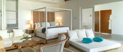 Quarto moderno com cama de dossel, um sofá, mesa de centro de madeira e um espaço de estar com cadeiras.