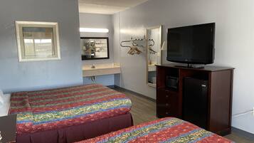 Quarto de hotel com duas camas, televisão, espelho, pia e armário.