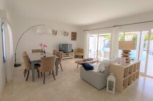 Uma sala de estar ampla com uma mesa de jantar, sofá e televisão.