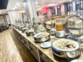 Disposição de buffet com diversos alimentos e utensílios de servir.