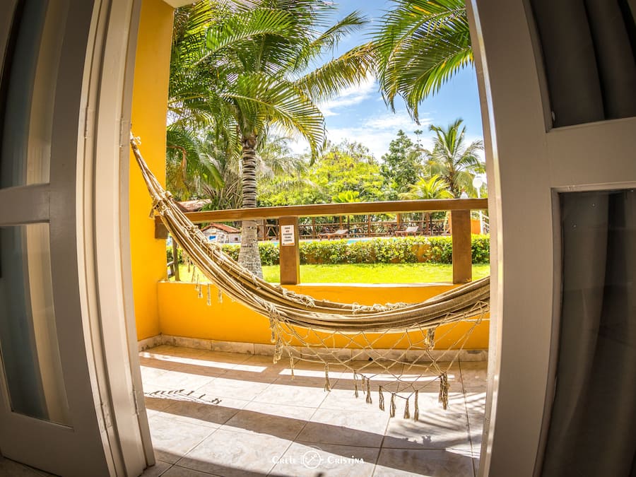 Uma rede em um quarto amarelo com vista para um jardim.