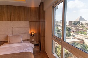 Quarto de hotel com uma grande janela que oferece vista das pirâmides.