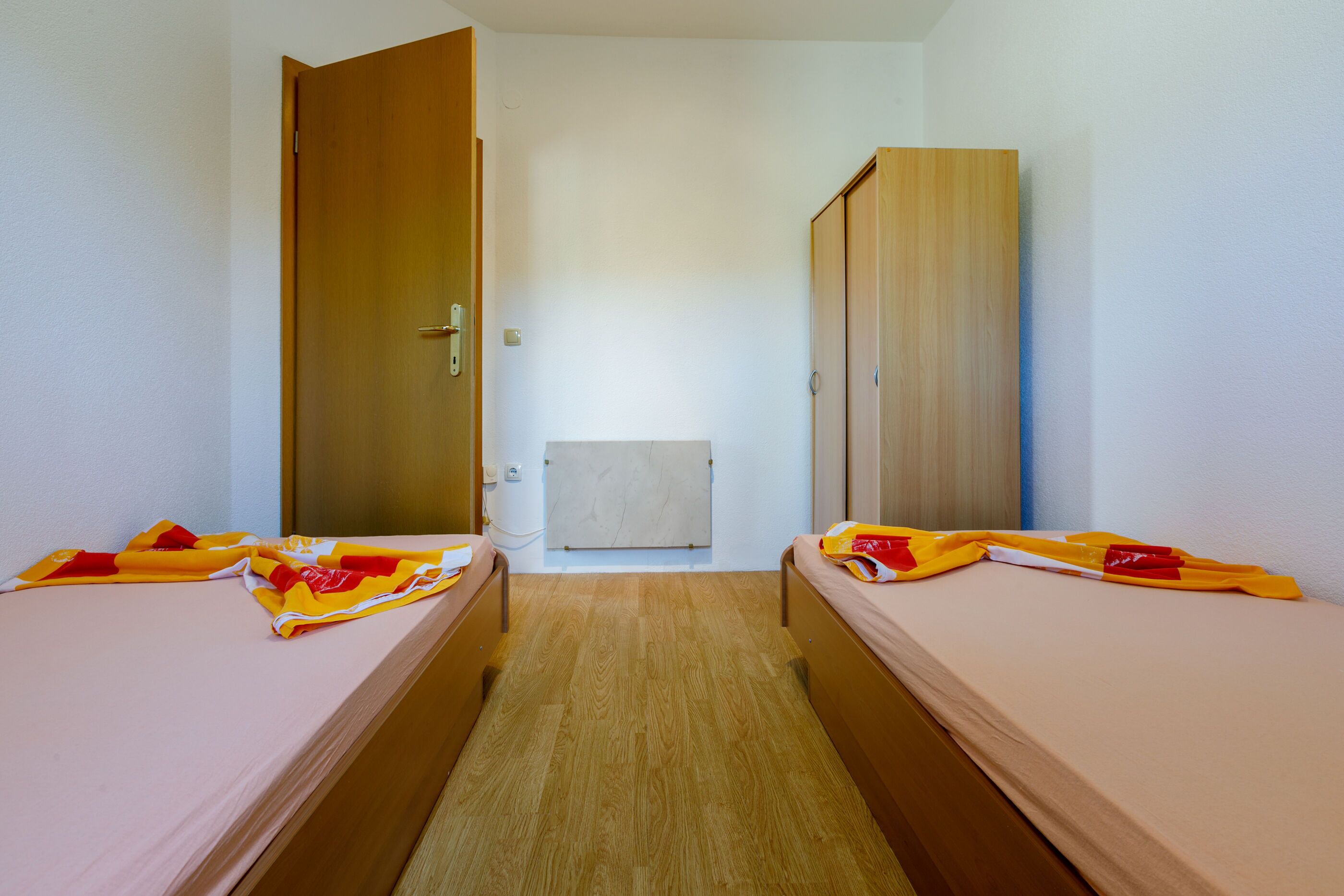Quarto com duas camas, um guarda-roupa e um radiador.