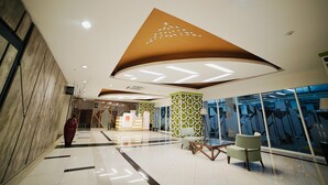 Um lobby moderno com balcão de recepção, área de estar e divisórias de vidro.
