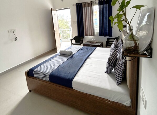 Quarto com cama de madeira, uma mesinha, uma cadeira e um vaso de planta.