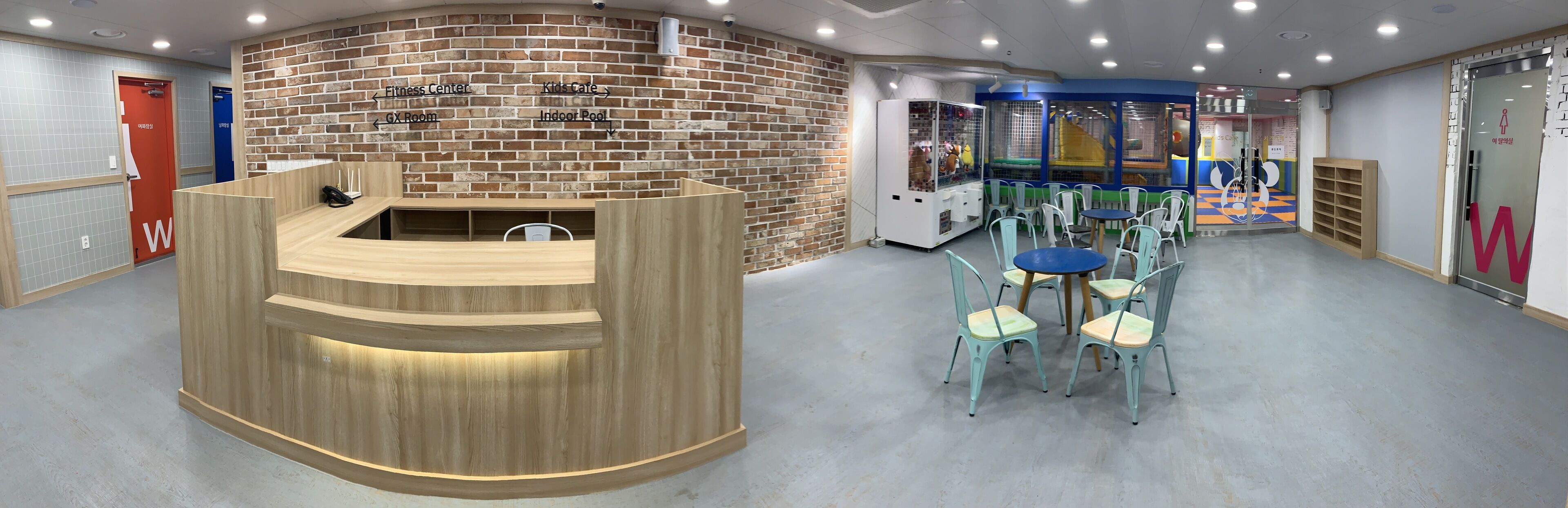 Uma receção com design em madeira, centro de fitness, café infantil e piscina interior.
