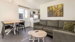Uma sala de estar moderna com um sofá cinzento, uma mesa de centro de madeira e um espaço de jantar com uma mesa e cadeiras.