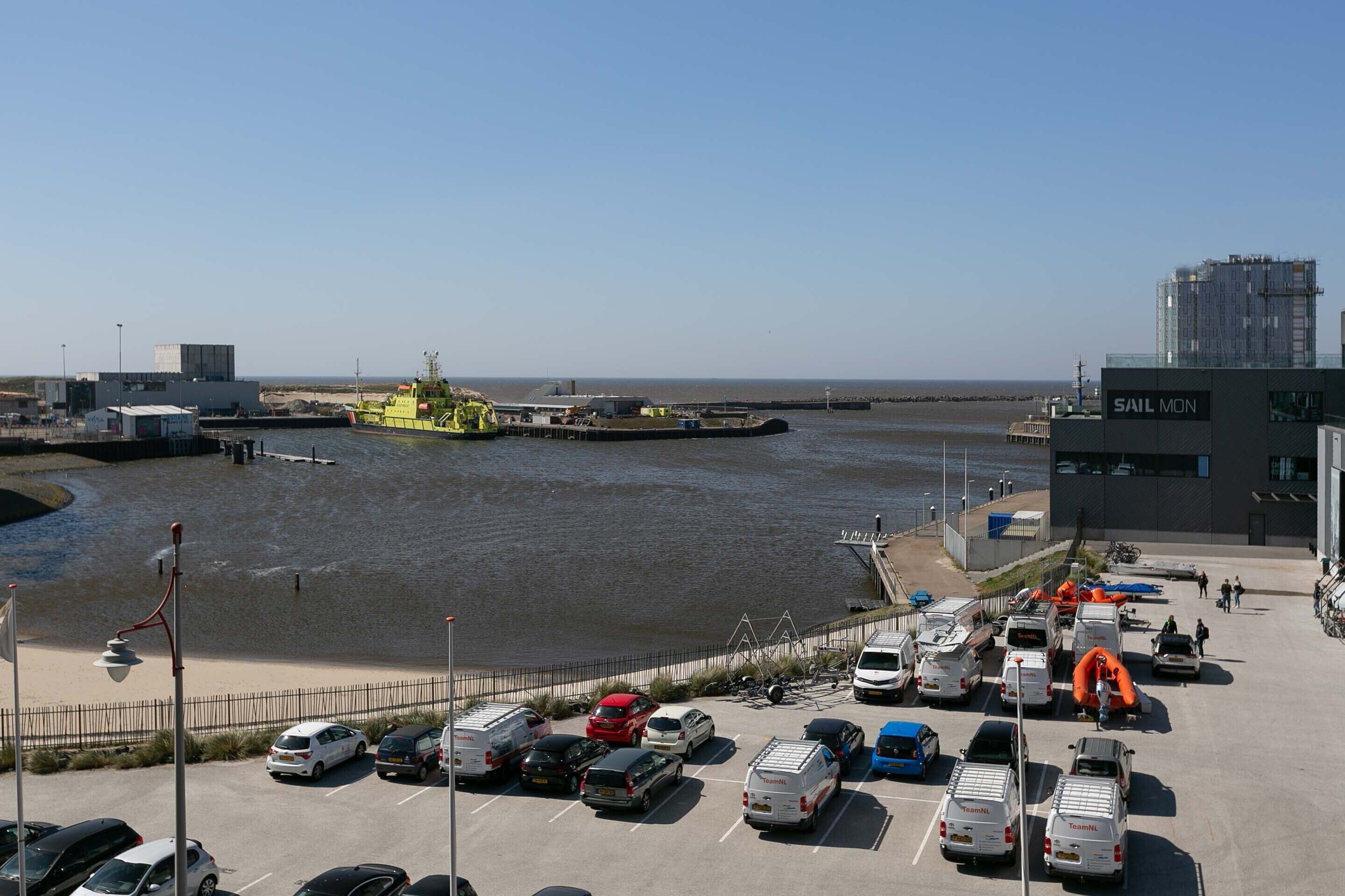 Uma área de estacionamento costeira com veículos e um cais de ferry.