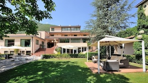 Uma casa moderna de dois andares com varanda coberta, piscina e gramado bem cuidado.