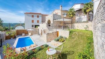 Uma villa com piscina, área de estar ao ar livre e fachada de pedra.