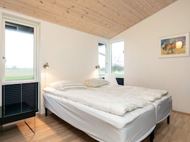 Quarto com cama, duas luminárias de cabeceira, uma janela e um quadro na parede.