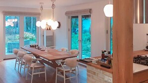 Uma cozinha moderna com mesa e cadeiras de madeira, janelas amplas e um pendente.