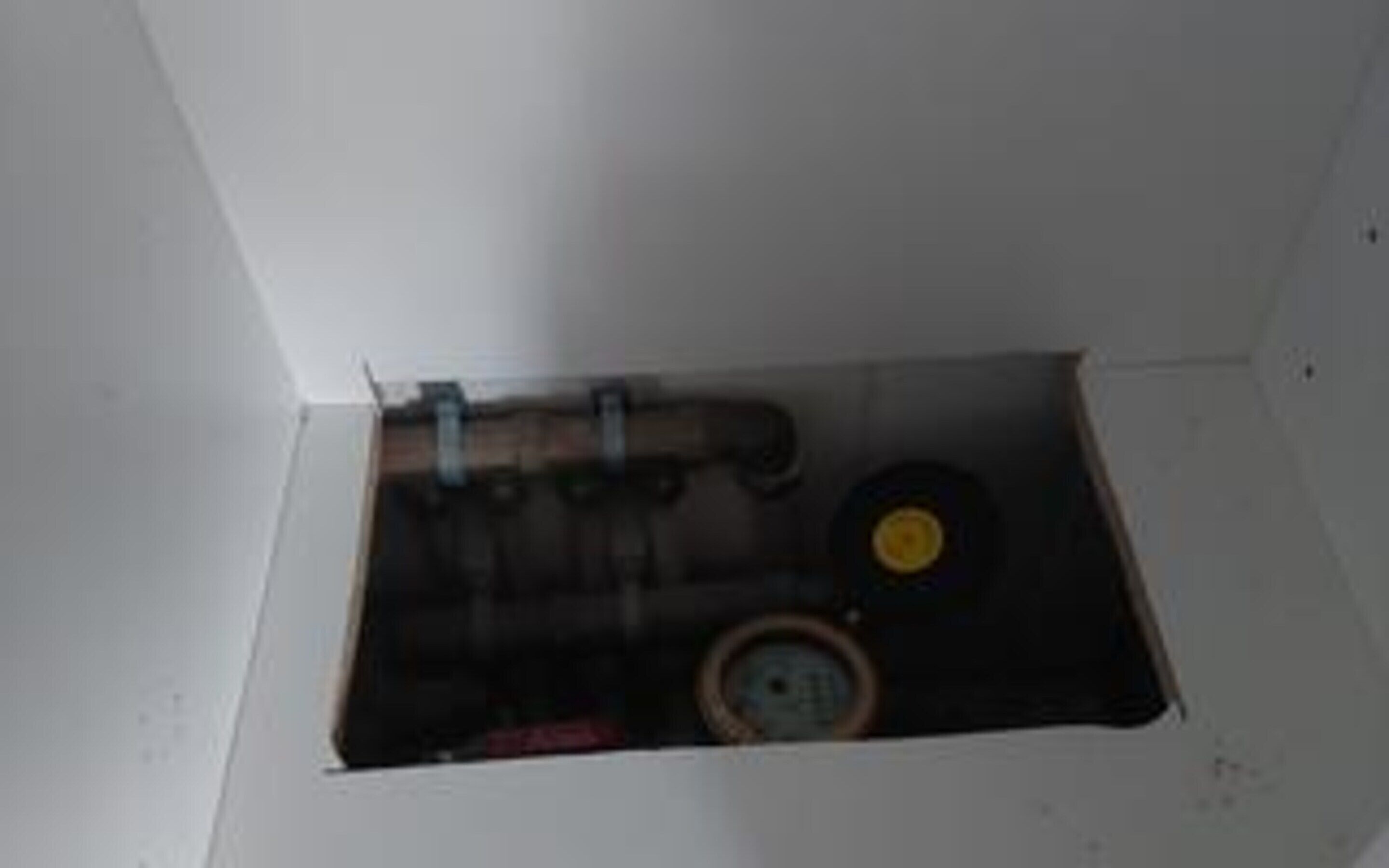 Um espaço pequeno e fechado, com uma janela, um cano e um objeto circular.