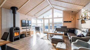 Uma sala de estar moderna com uma lareira a lenha, um sofá, uma mesa de centro e uma televisão.