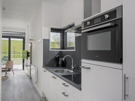 Uma cozinha moderna com forno embutido, cafeteira e janela com vista para uma paisagem verde.