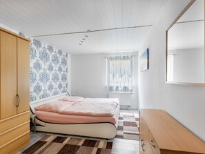 Quarto com cama, armário de madeira e janela com cortinas.