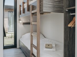 Um quarto com uma cama beliche, uma mesinha de cabeceira e uma janela.