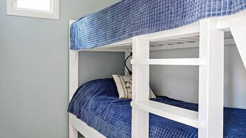 Uma cama beliche com colchão azul e estrutura branca num quarto com paredes azul claro.
