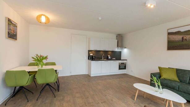 Espaço compacto com área de jantar, cozinha compacta e sofá.