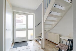 Uma escadaria que leva a um andar superior, uma porta com vista e uma cadeira.