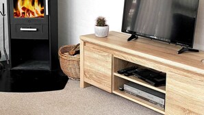 Sala de estar moderna com lareira a lenha, televisão de tela plana e móvel para entretenimento em madeira.