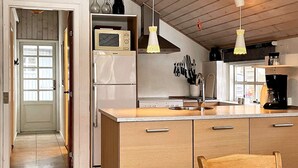 Uma cozinha com armários de madeira, bancada, pia e luminárias pendentes.