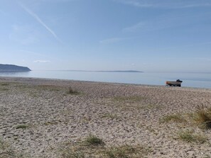 Uma praia com um barco na areia e uma linha de costa distante.