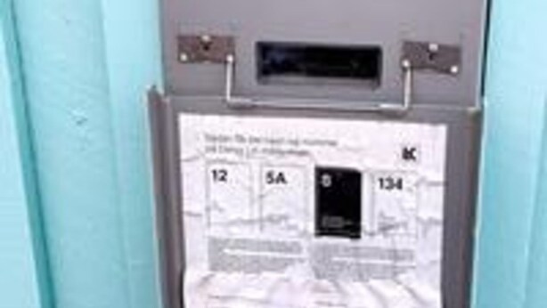 Caixa de contador de serviços fixada numa parede azul-claro, com um papel colado.