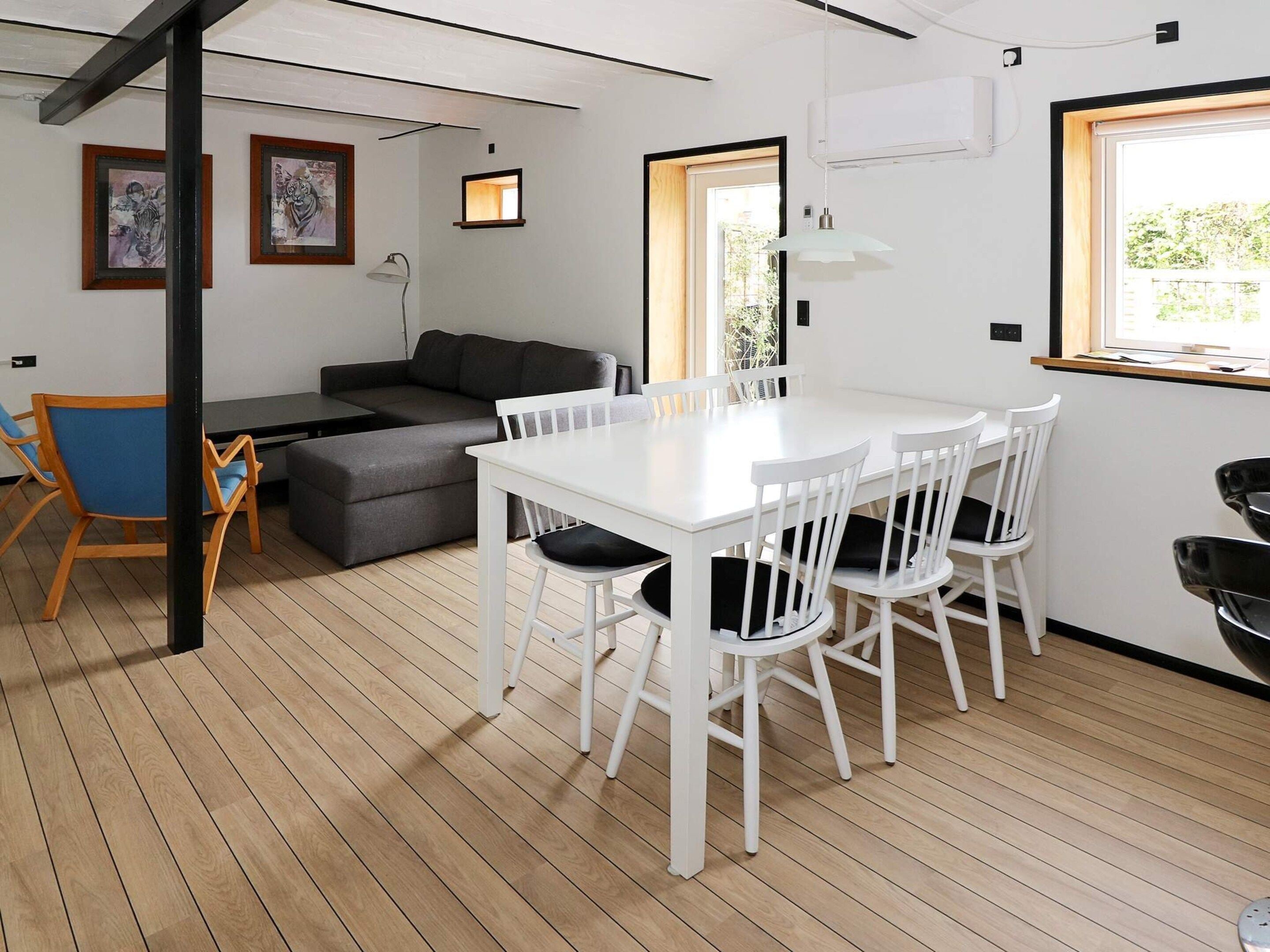 Um interior moderno com mesa de jantar, cadeiras, sofá e obras de arte nas paredes.