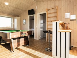 Quarto com mesa de bilhar, espaço de bar e cama.