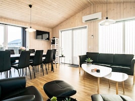 Um interior moderno com área de refeições, sofá e televisão fixada na parede.