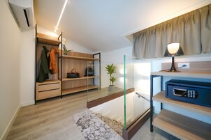 Quarto moderno com guarda-roupa embutido, guarda-corpo de vidro, micro-ondas e um vaso com planta.