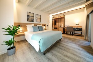 Quarto de hotel moderno com uma cama, mesas de cabeceira, escrivaninha e guarda-roupa.