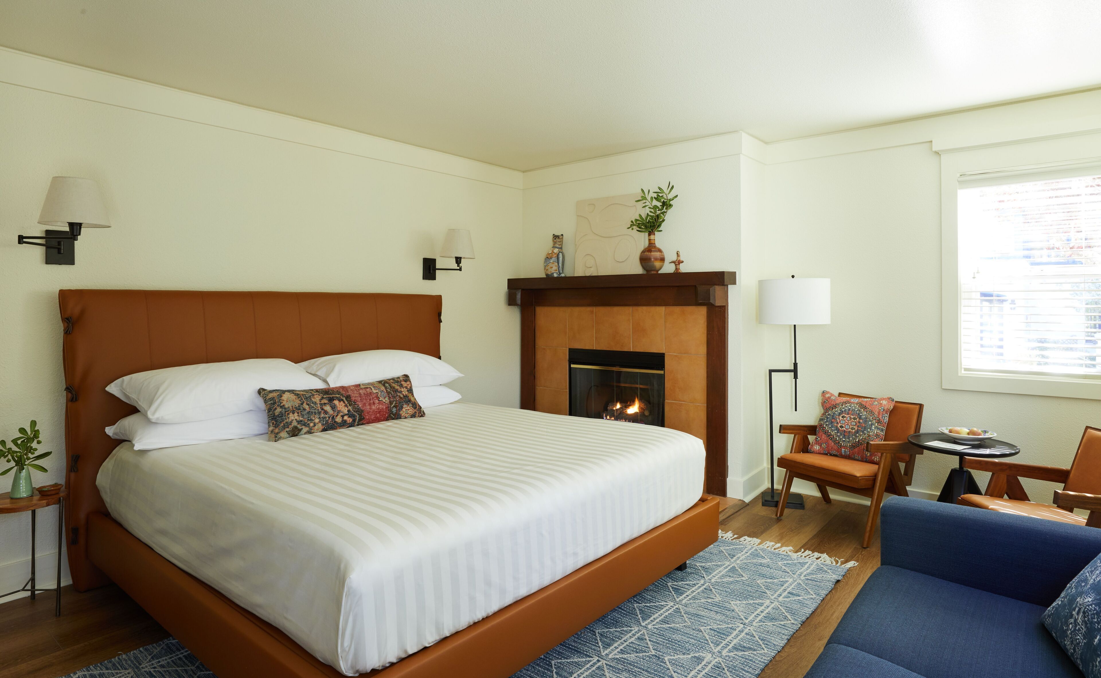 Quarto de hotel com uma cama grande, lareira, sofá e área de jantar.
