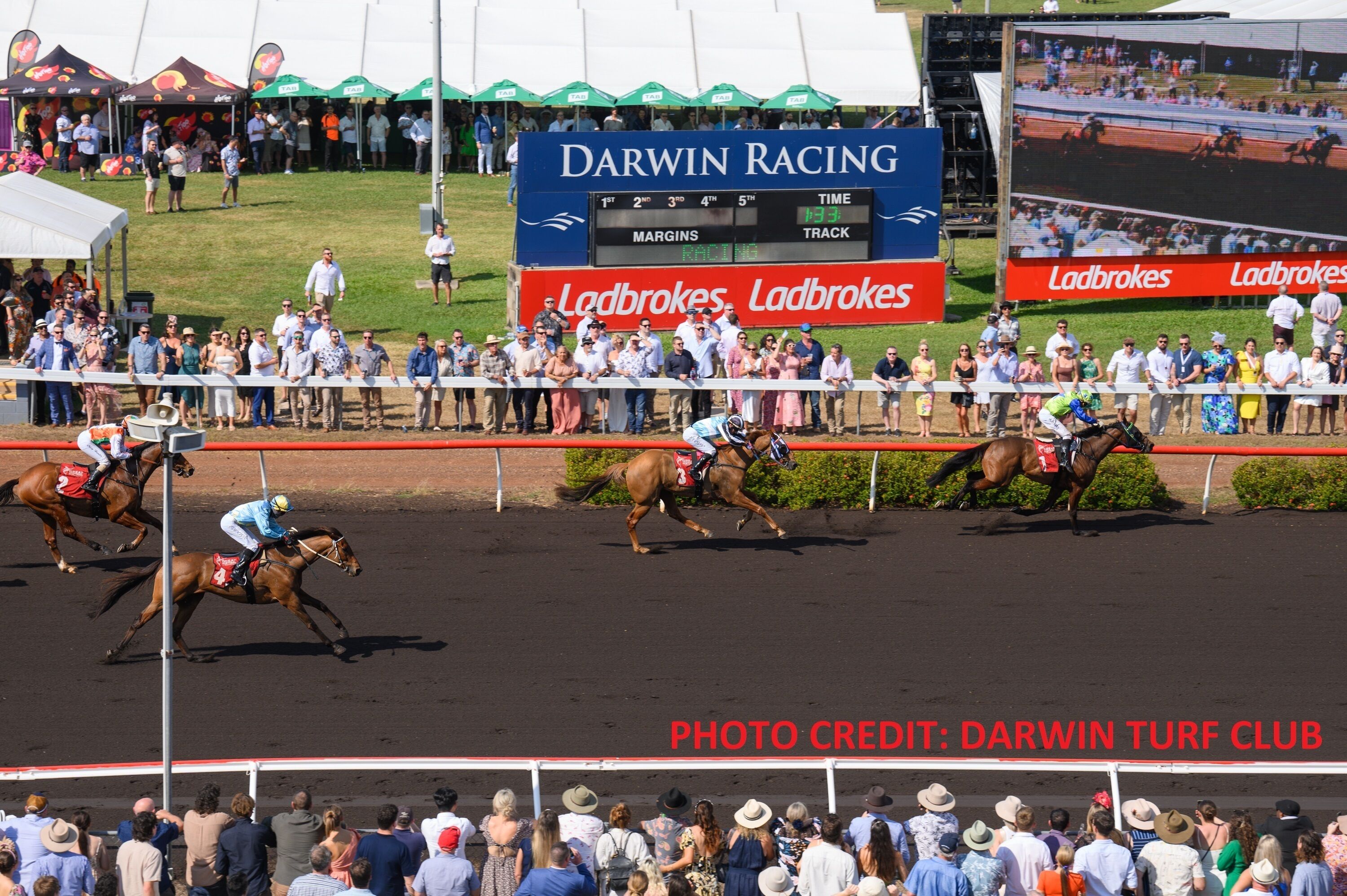 Corrida de cavalos em Darwin Racing, com espectadores nas arquibancadas.