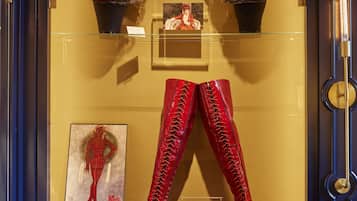 Uma vitrine com botas estampadas em vermelho e preto, uma grinalda vermelha e uma moldura com uma fotografia.
