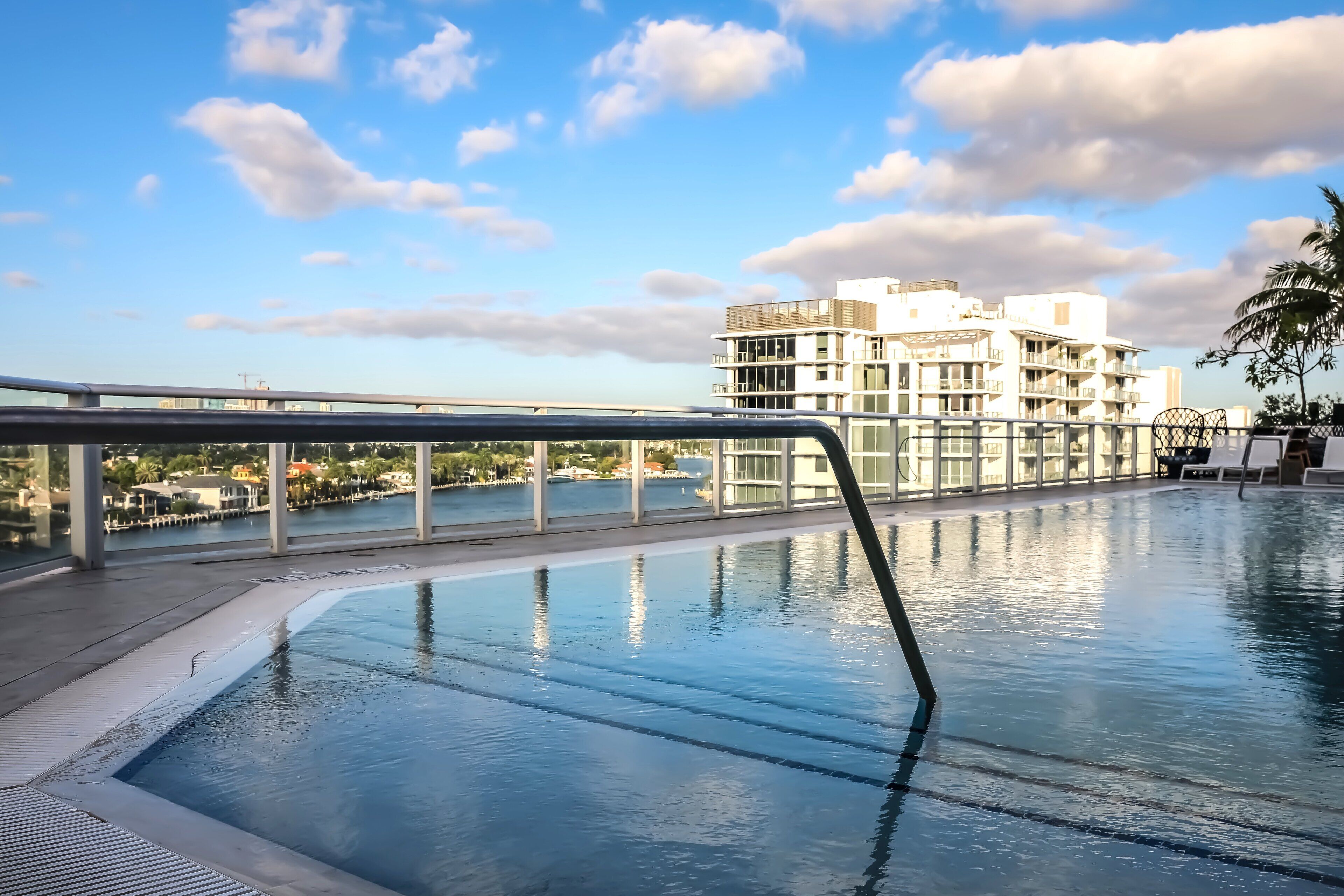 Piscina interna com barreira de vidro, vista de um edifício moderno e céu claro.