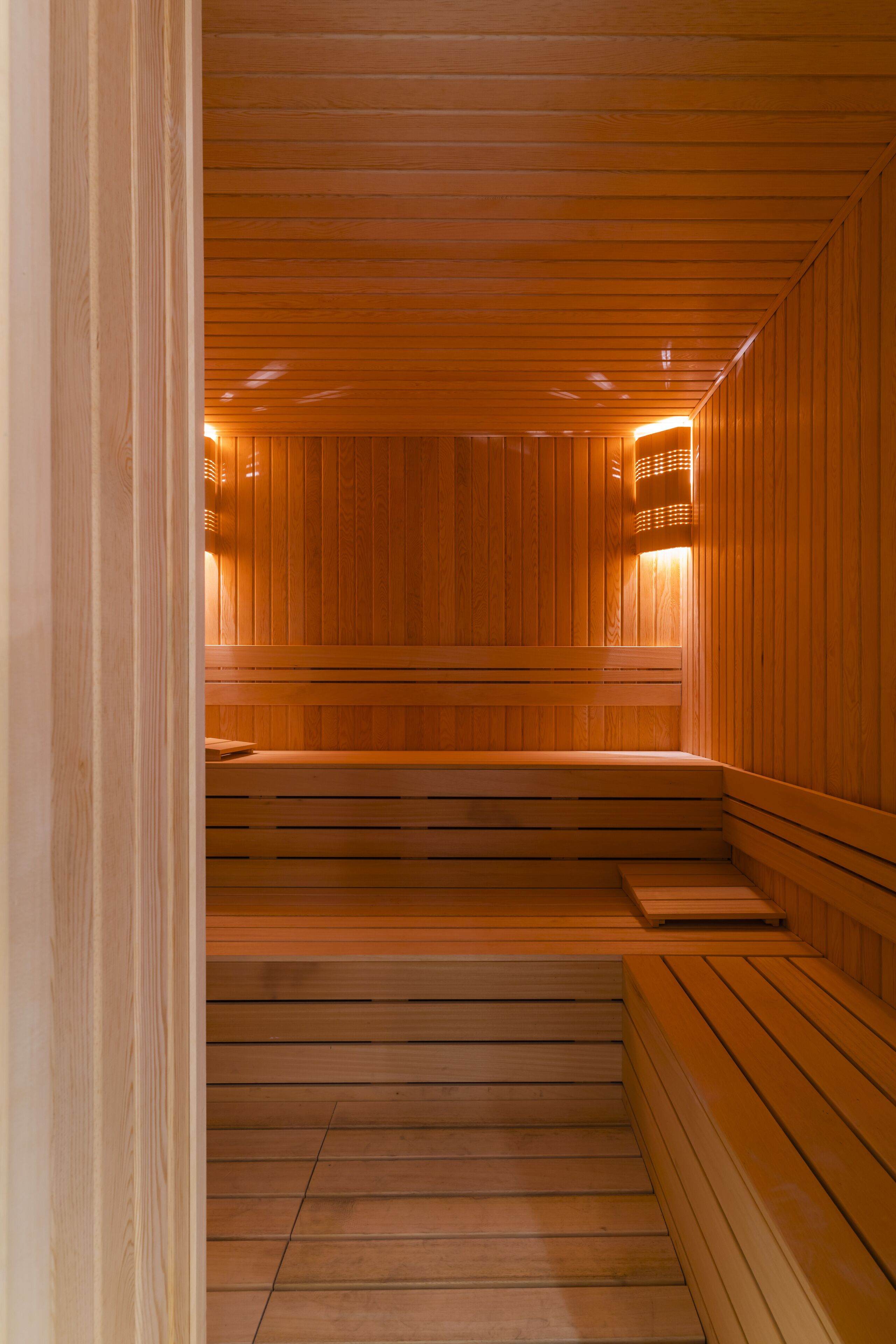 Uma sauna de madeira com bancos e piso inclinado.