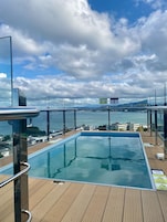 Piscina no terraço com vista desobstruída para uma ponte e paisagem urbana ao fundo.
