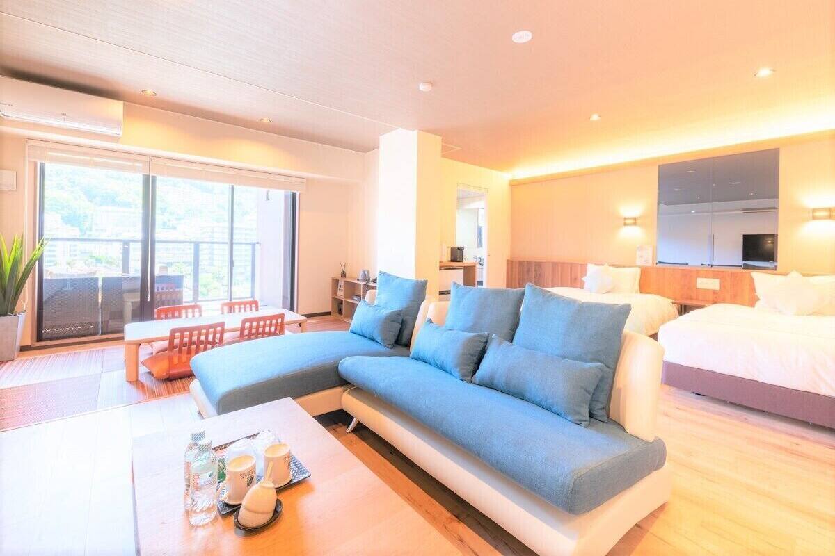 Uma sala moderna com sofá seccional, área de refeições e quarto com cama.