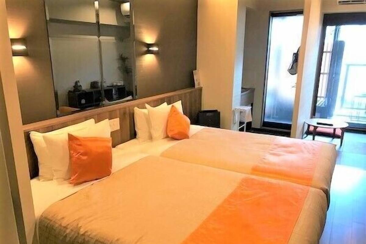 Quarto de hotel com duas camas, um espelho grande e vista para o exterior.
