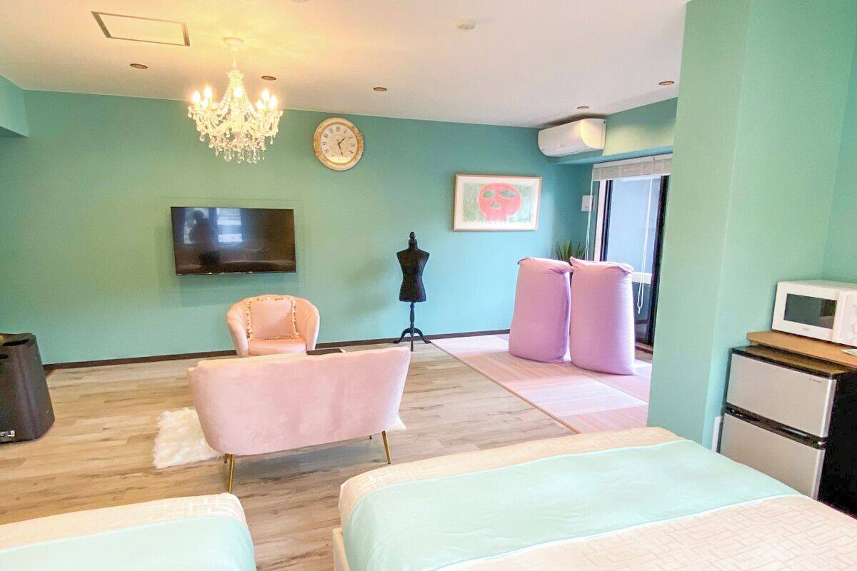 Quarto de hotel com duas camas, televisão, candelabro, relógio e quadro na parede.