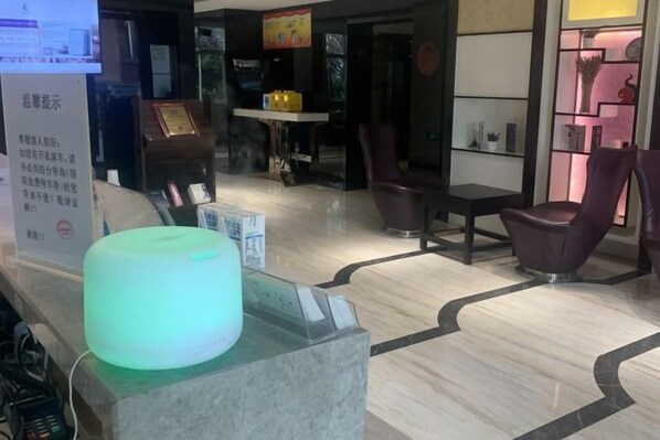 Uma área de recepção com design moderno, com balcão de atendimento, espaço para sentar e uma parede decorativa.