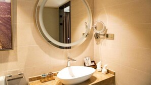 Uma casa de banho moderna com um espelho redondo grande, uma sanita branca e um porta-toalhas.
