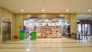 Uma loja de conveniência Lawson com fachada de madeira, prateleiras abastecidas e um elevador visível.
