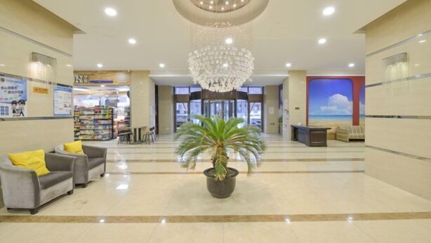 Um hall amplo com um candelabro, um balcão de recepção e uma área de estar com sofás.