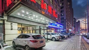 Hotel com uma fila de carros estacionados e uma entrada bem iluminada.